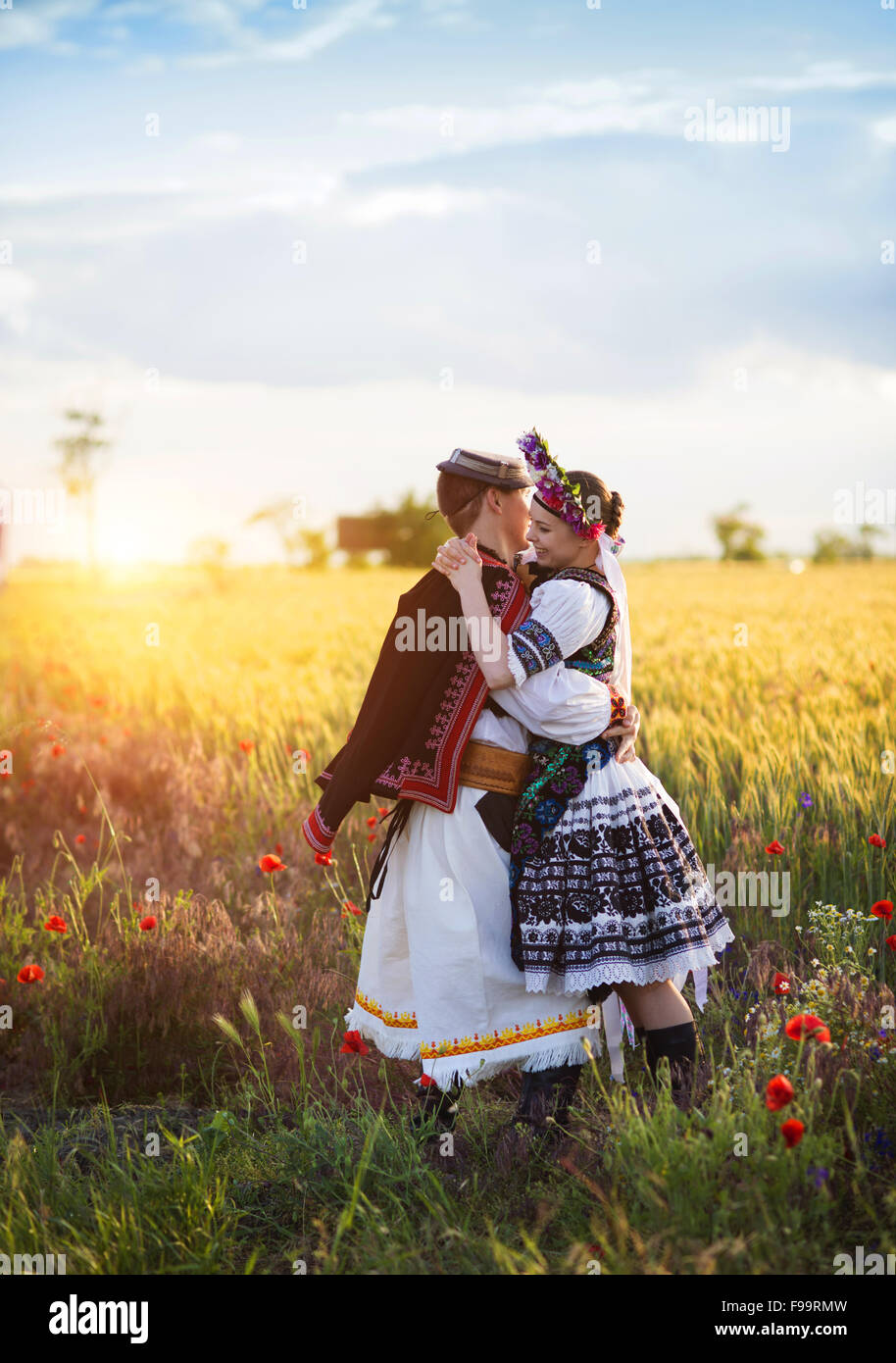 Love couple in sunset field. They wearing traditional Eastern Europe ...