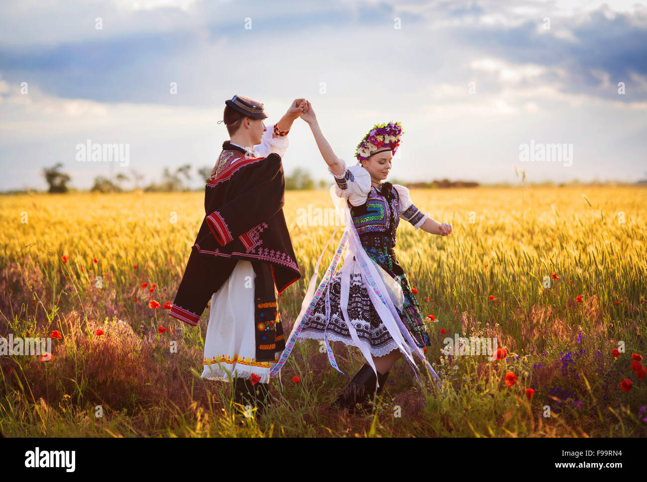 Love couple in sunset field. They wearing traditional Eastern Europe ...