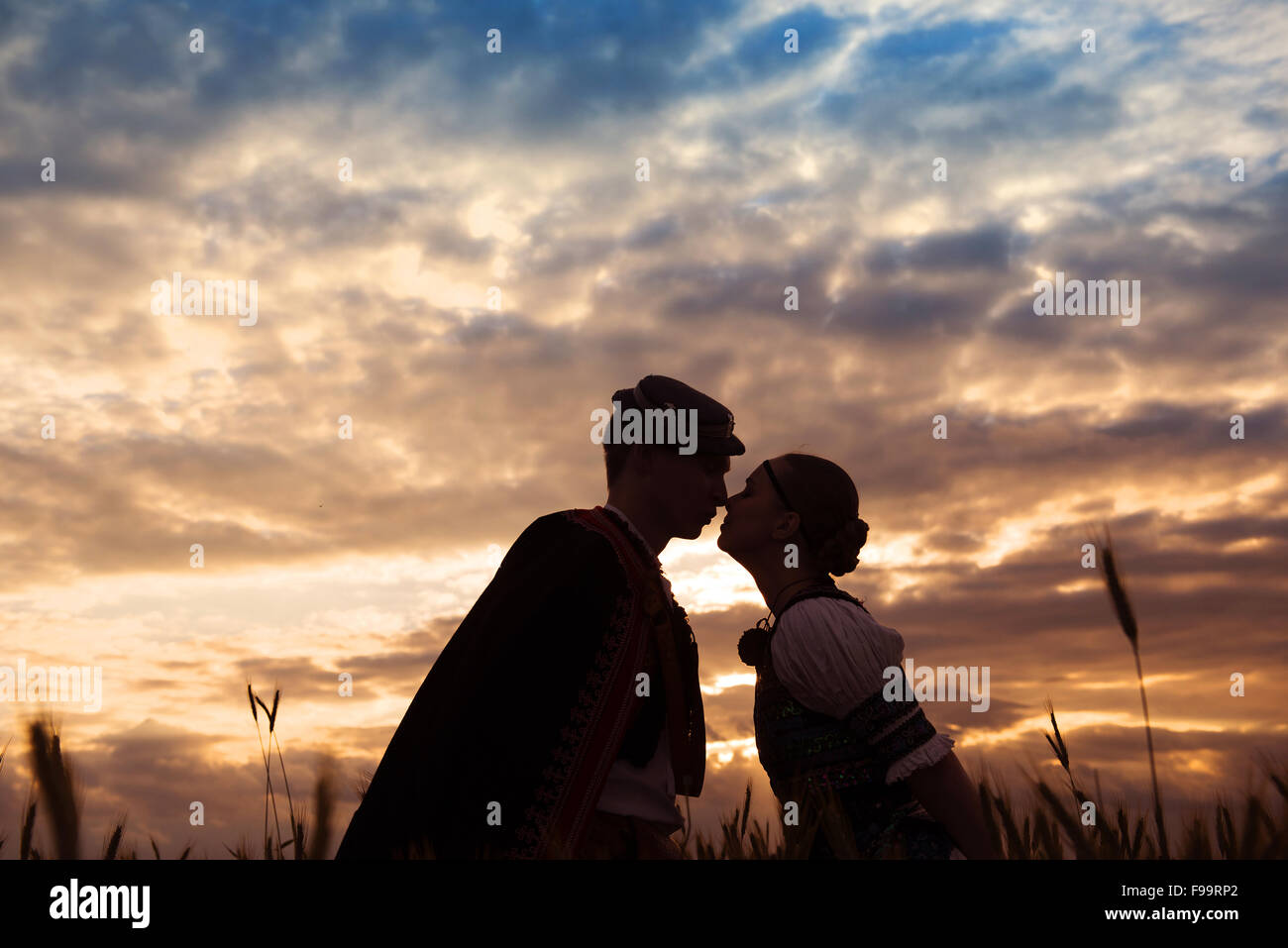 Love couple in sunset field. They wearing traditional Eastern Europe ...