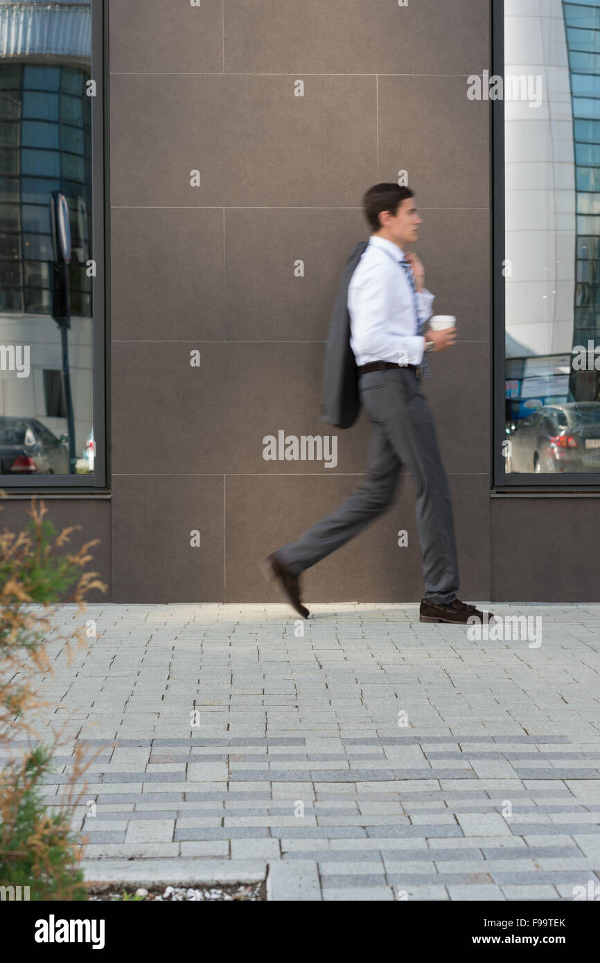 Side view of young businessman walking in passage of office Stock Photo ...