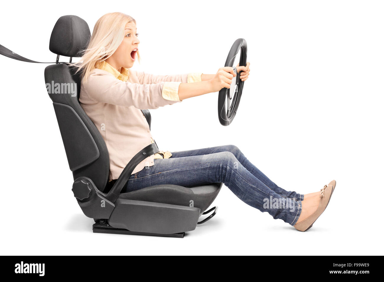 Young blond woman driving very fast seated on a car seat fastened with ...