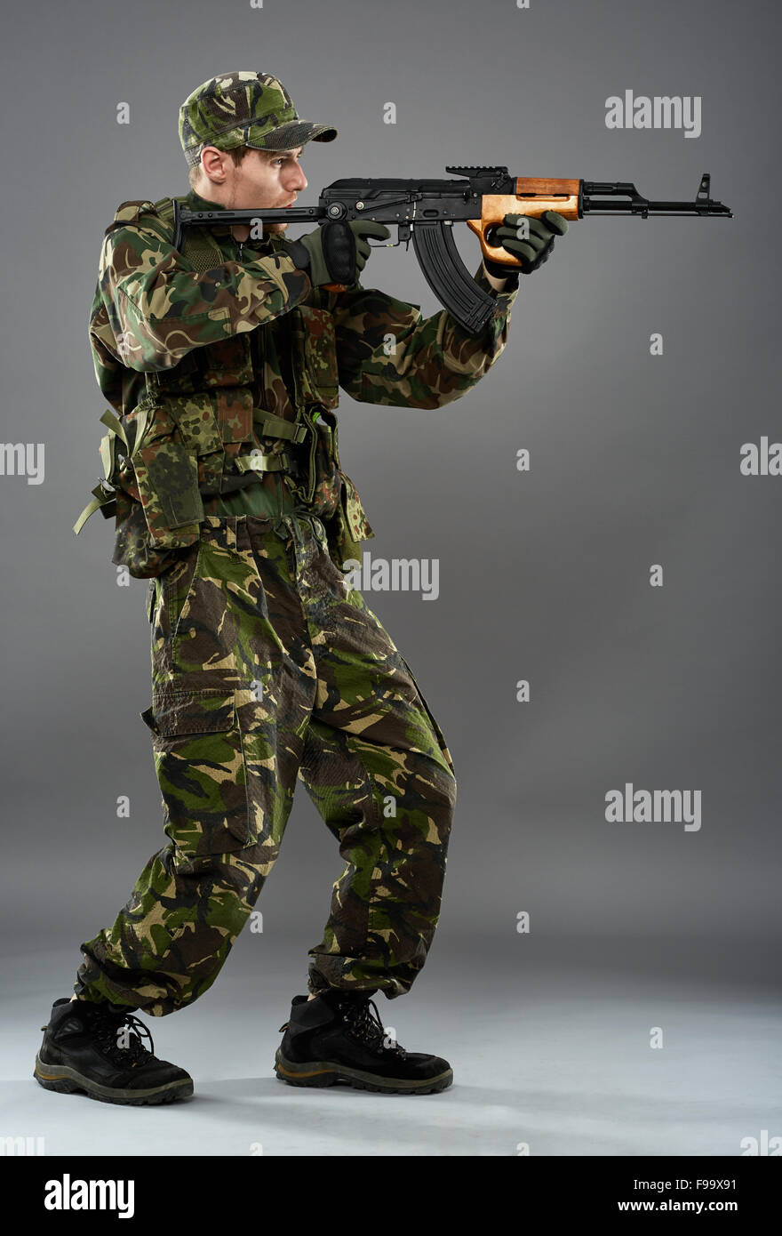 Studio portrait of an young soldier in uniform with machine gun, over ...