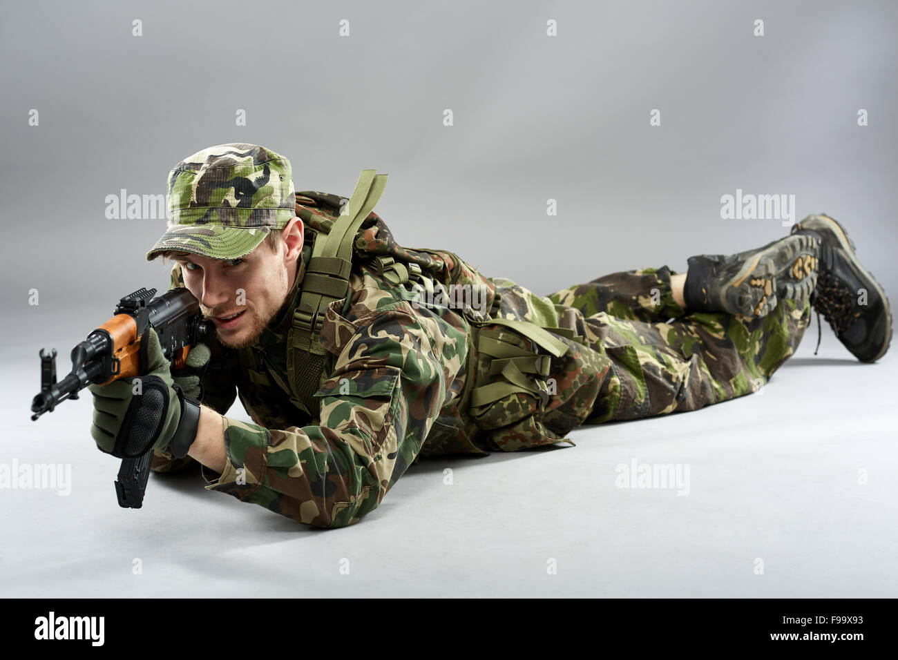 Soldier in camouflage uniform aiming the target from laying down ...