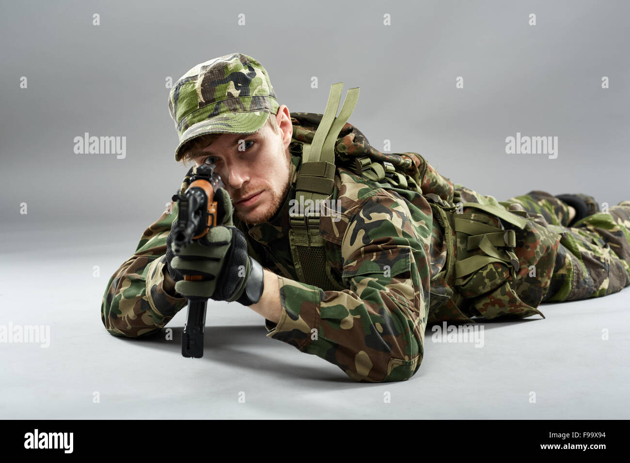 Soldier in camouflage uniform aiming the target from laying down ...