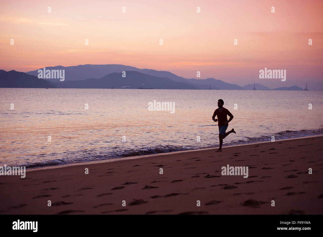 Young man running on the beach at sunset Stock Photo - Alamy
