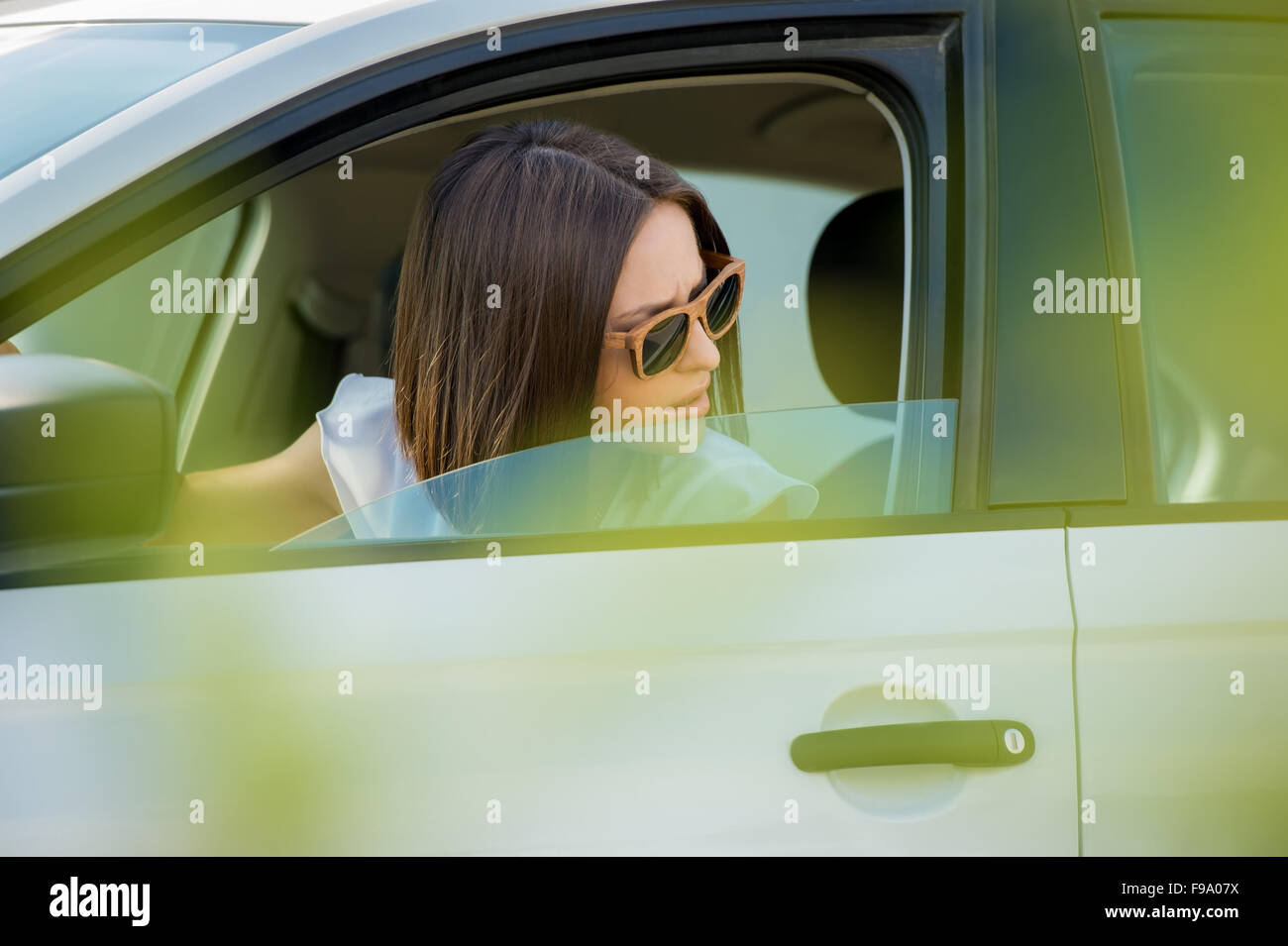 Girl wearing sunglasses driving white car Stock Photo - Alamy