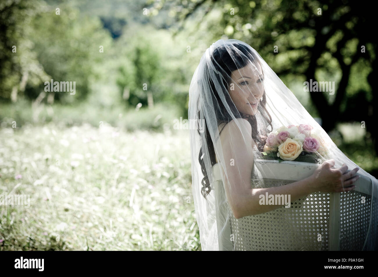 Bride in white wedding dress sitting on chair at the meadow Stock Photo ...
