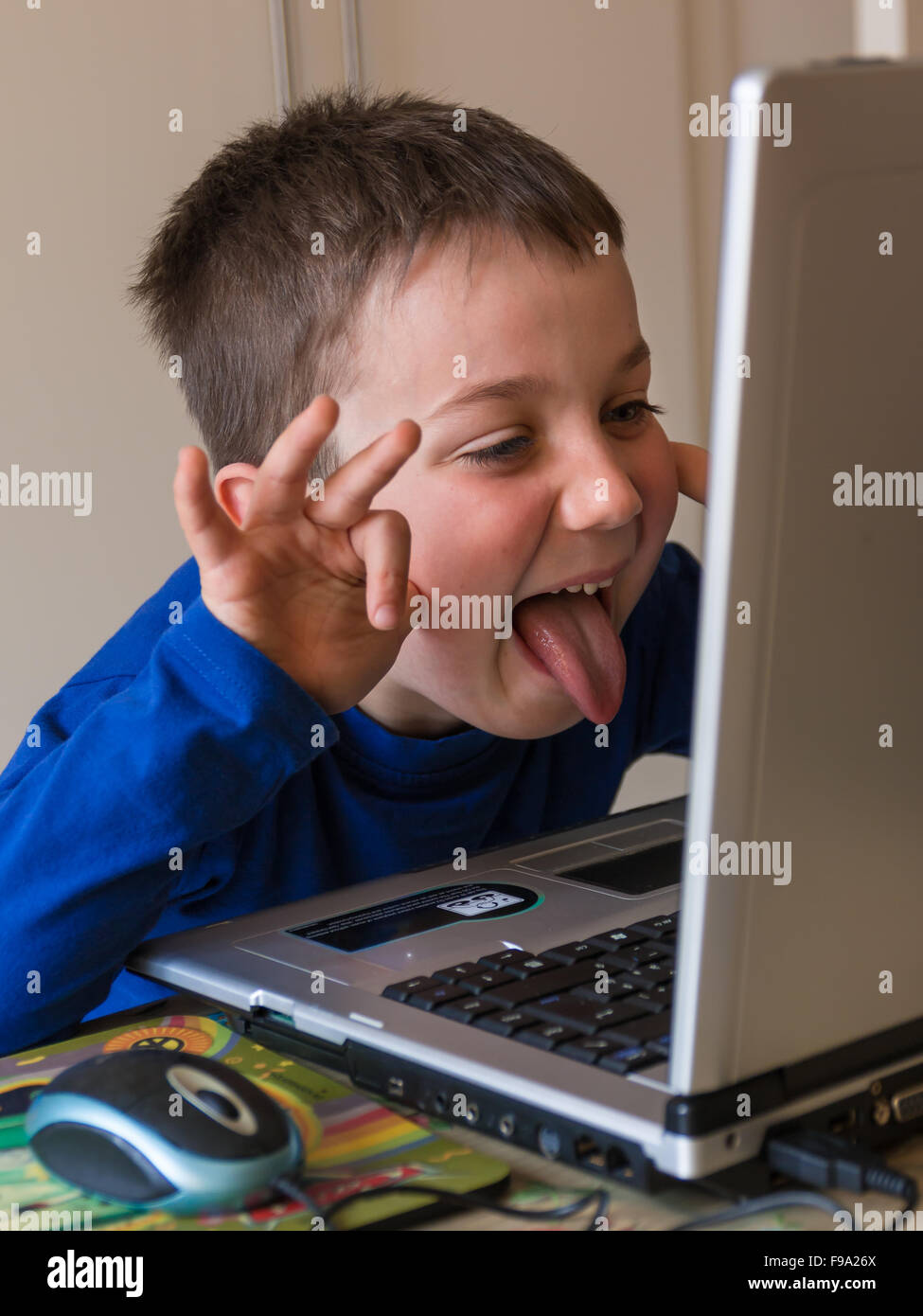 Joking Child in Front of Touch Screen Laptop, tongue stuck out Stock ...
