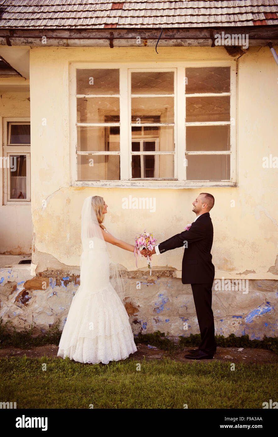 Happy bride and groom posing by the old house Stock Photo - Alamy