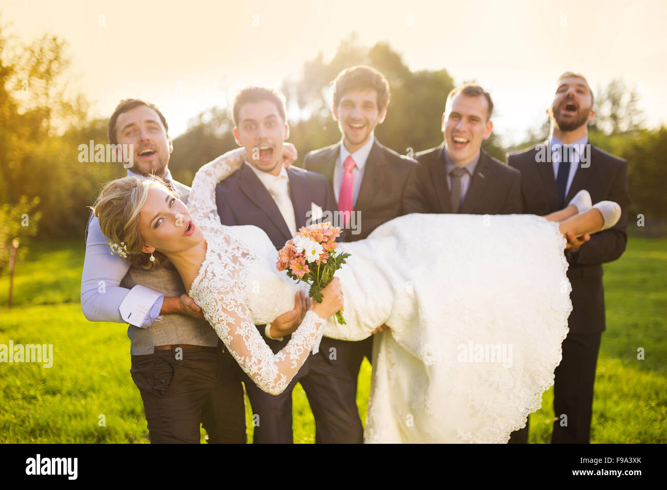 Outdoor portrait of young groom with his friends holding beautiful ...