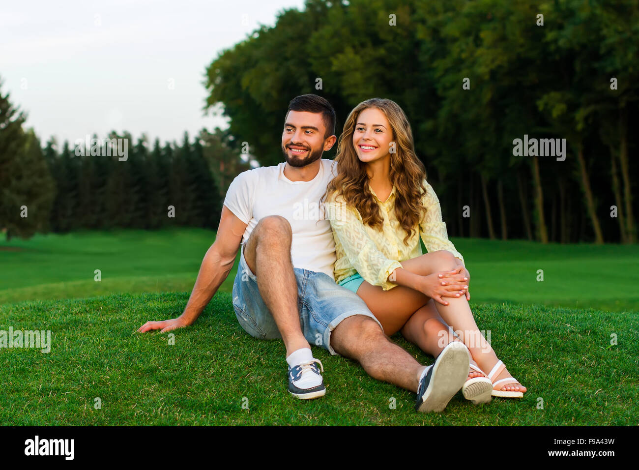 Lovers sit on the grass and hugging Stock Photo - Alamy