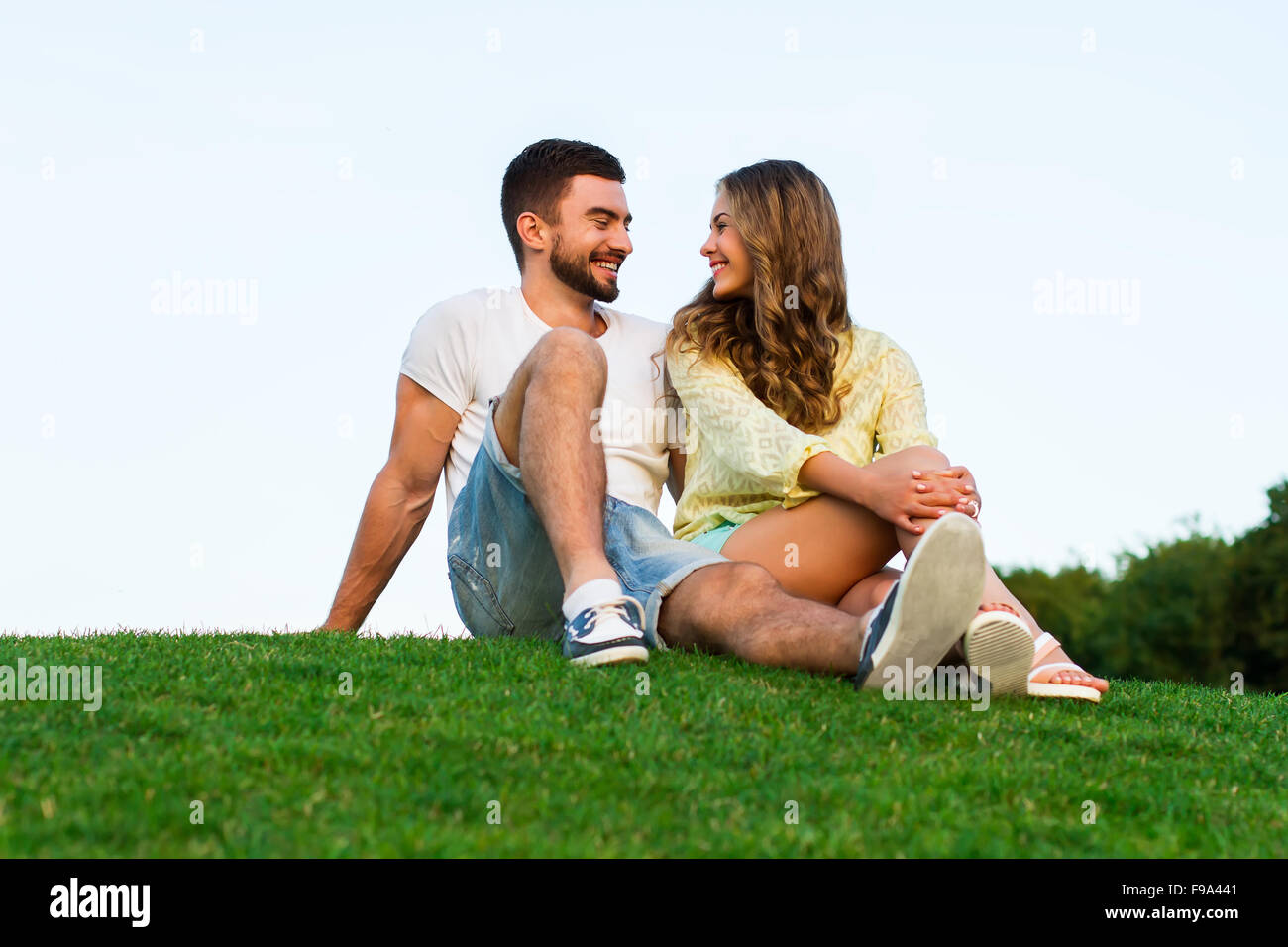 Romantic trip. Lovers sit on the grass Stock Photo - Alamy