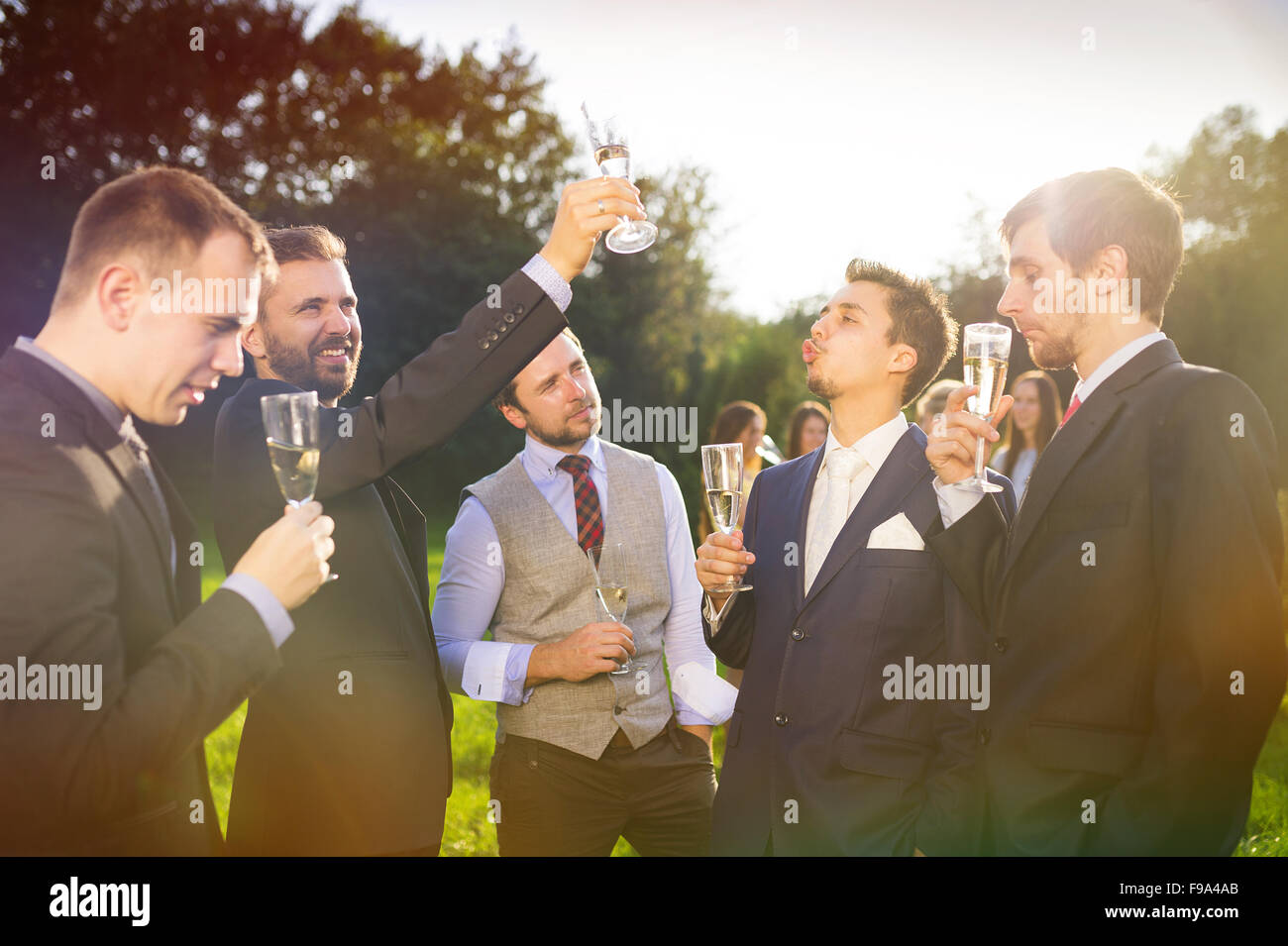 Groom with four happy groomsmen toasting at the wedding reception ...