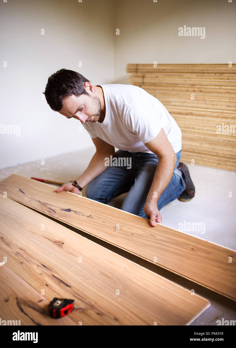 Young handyman installing wooden floor in new house Stock Photo - Alamy