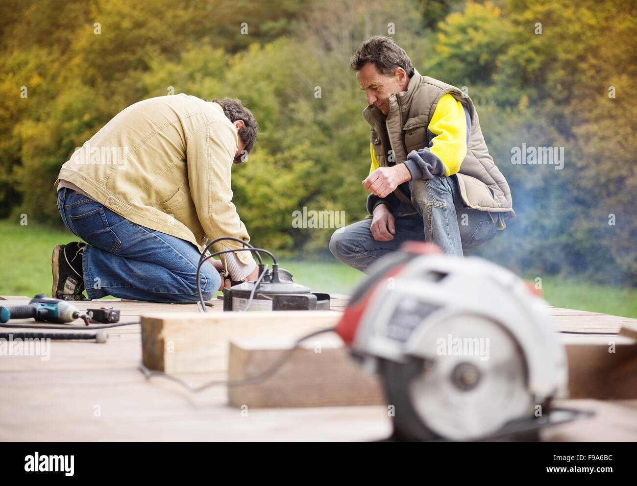 Two carpenters grinding wooden planks outside in terrace Stock Photo ...
