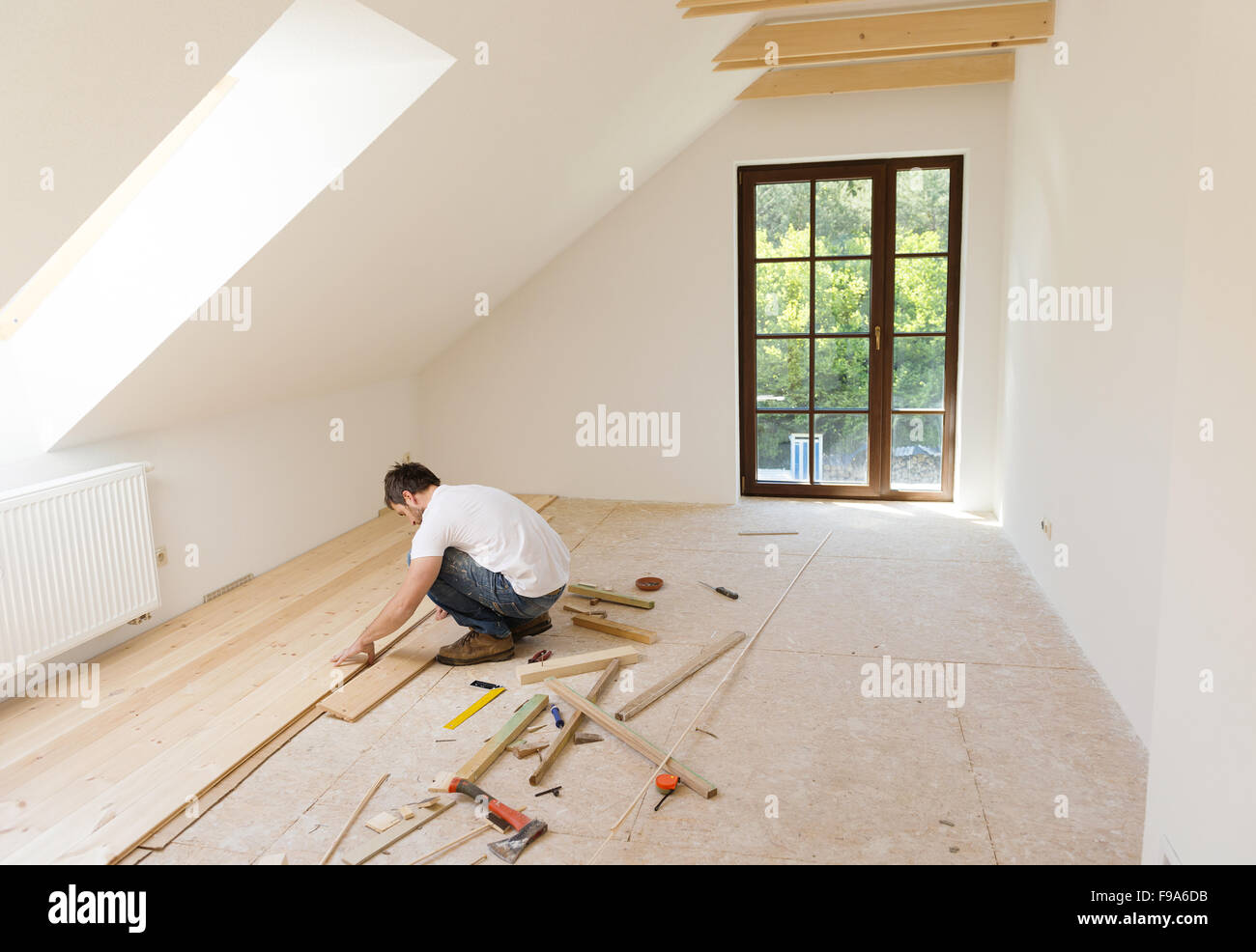 Handyman installing wooden floor in new house Stock Photo - Alamy