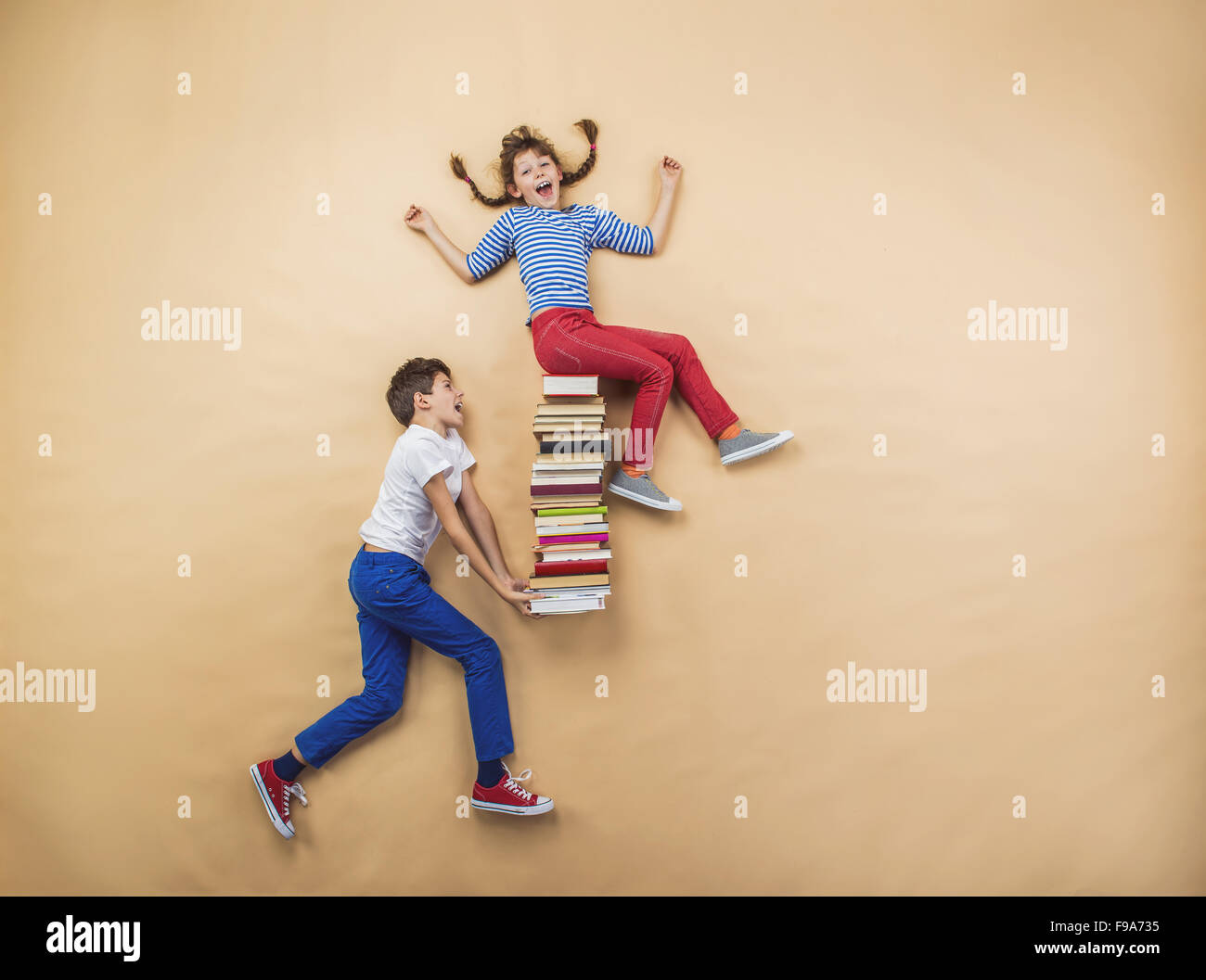 Happy children playing with group of books in studio Stock Photo - Alamy