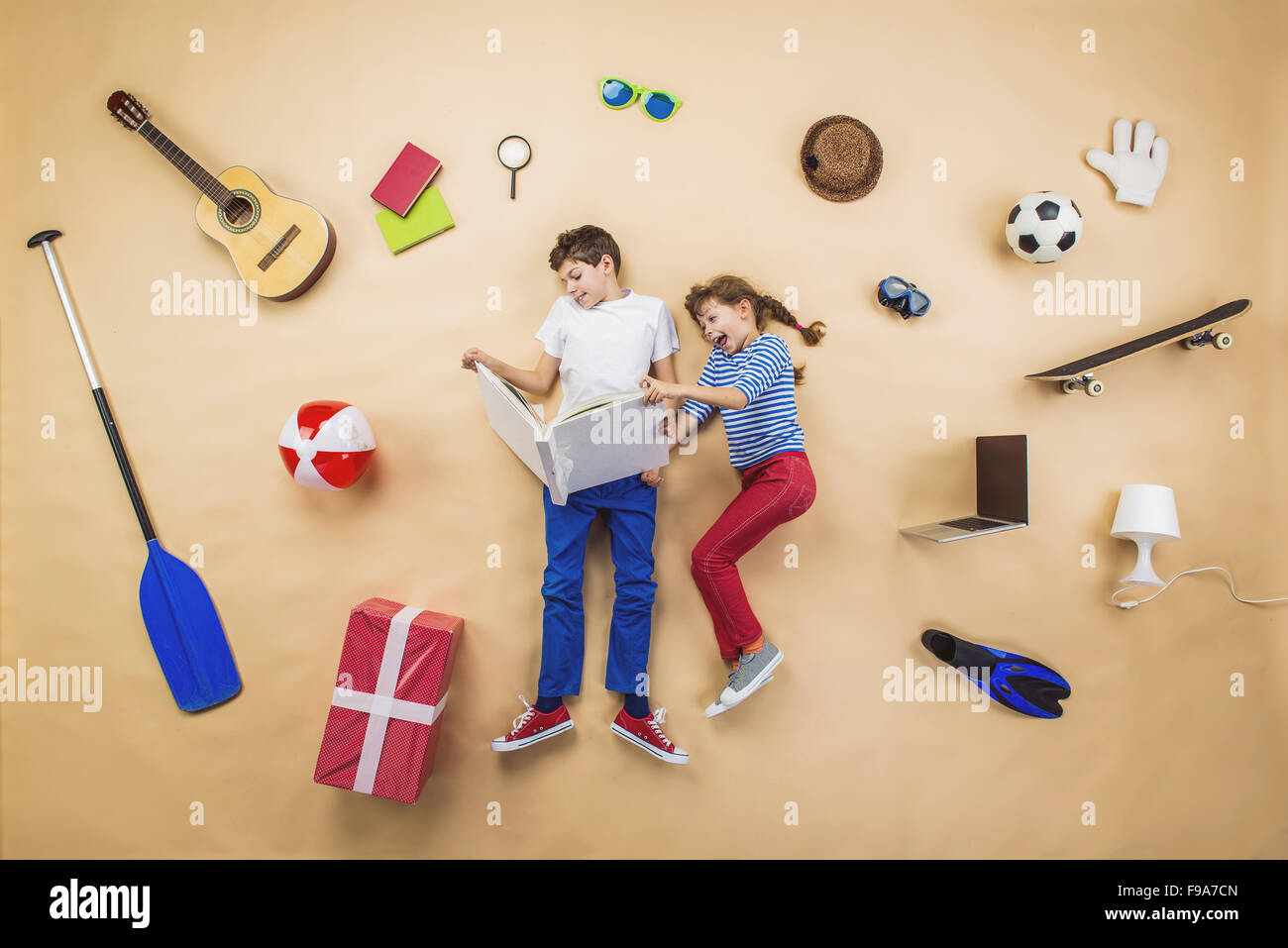 Happy children are reading book on the floor with group of objects ...