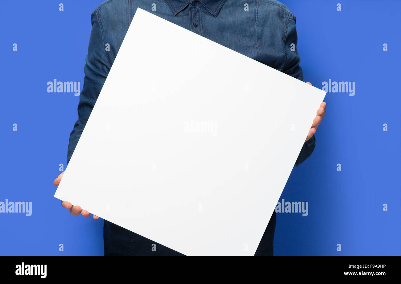 male person holding a white blank sign in blue back Stock Photo - Alamy