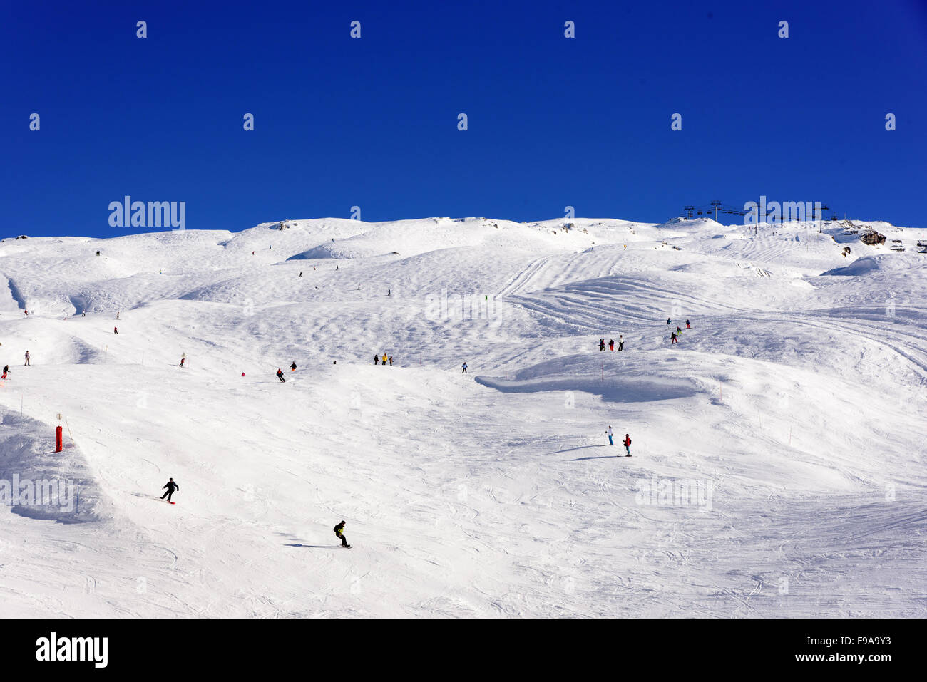 Wide area of ski slopes with a lot of rounded hills and skiers spread ...