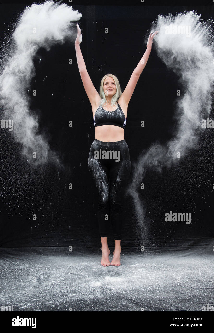A young female girl model dancing in a cloud of white talcum powder ...
