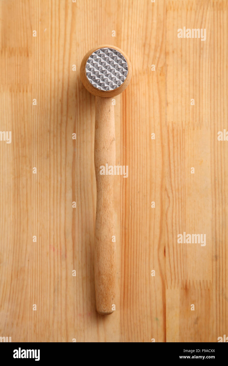 Hammer for beating the meat with a wooden handle isolated on wooden ...