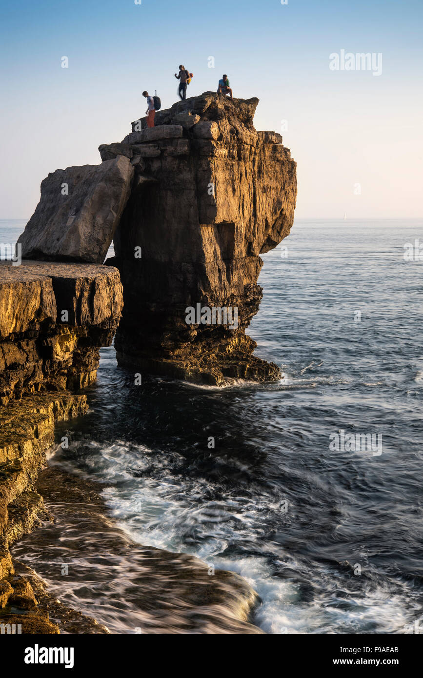 Rocky cliff landscape with sunset over ocean with unidentified people ...