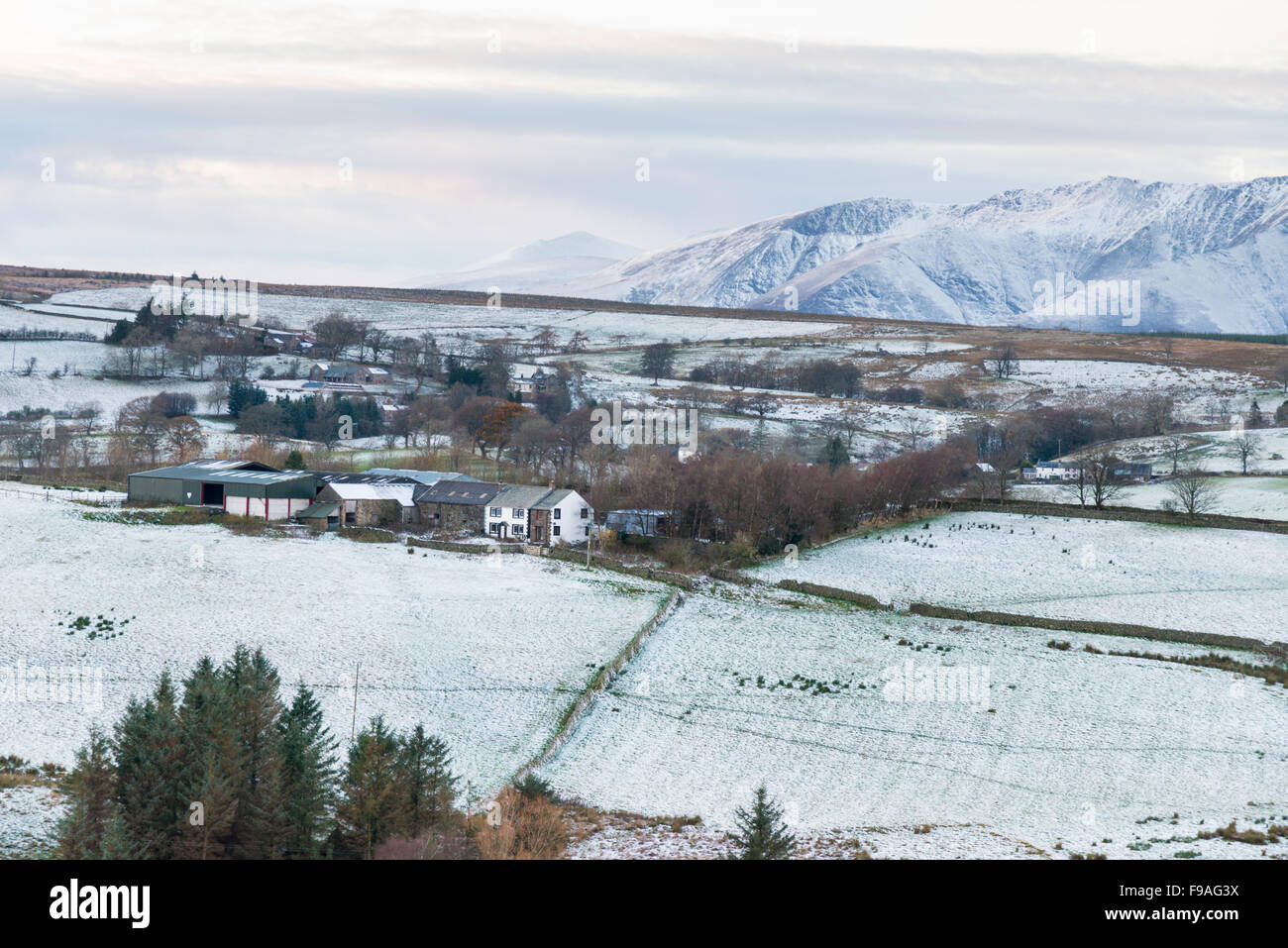 A snowy landscape of Cumbrian farms, buildings and mountains near ...