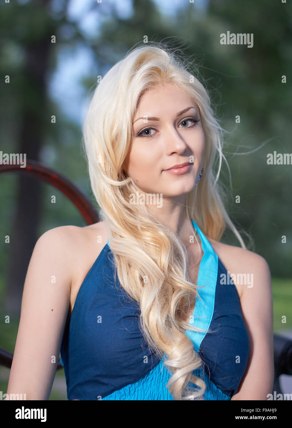Portrait of the beautiful blond girl on the green blurry background of ...