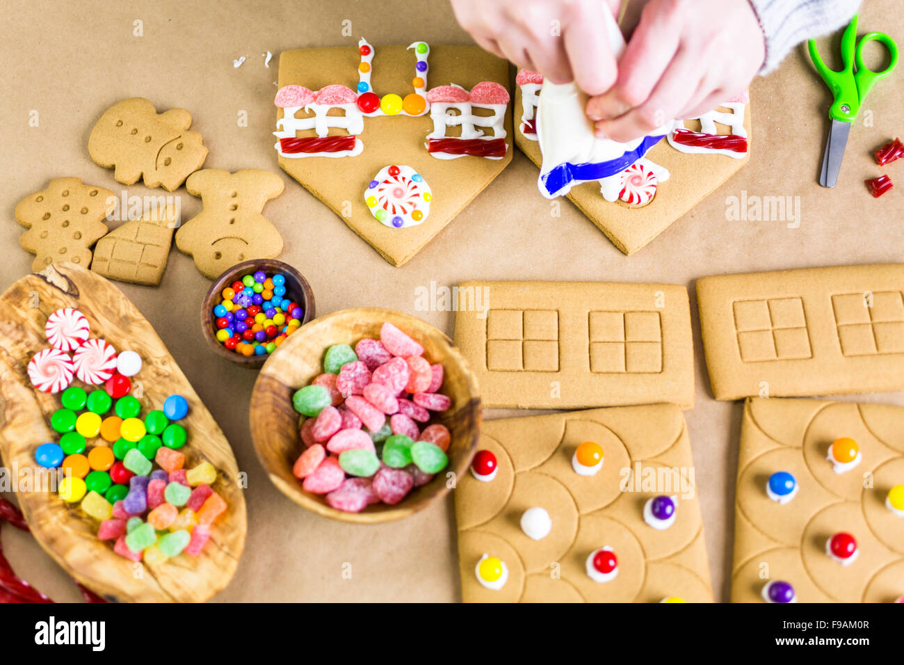 Decorating gingerbread house with royal icing and colorful candies ...