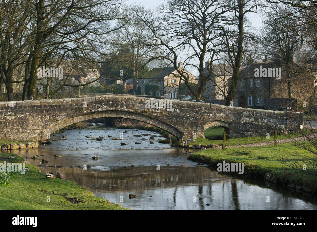 Ancient, rustic, stone packhorse bridge with 2 arches, spanning Linton ...