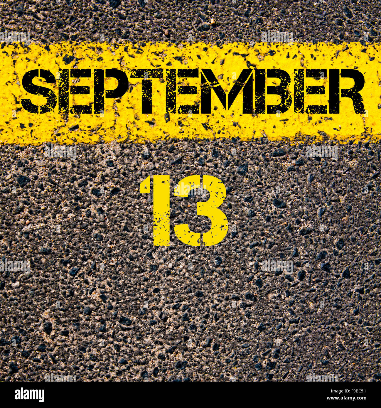 13 September calendar day written over road marking yellow paint line ...