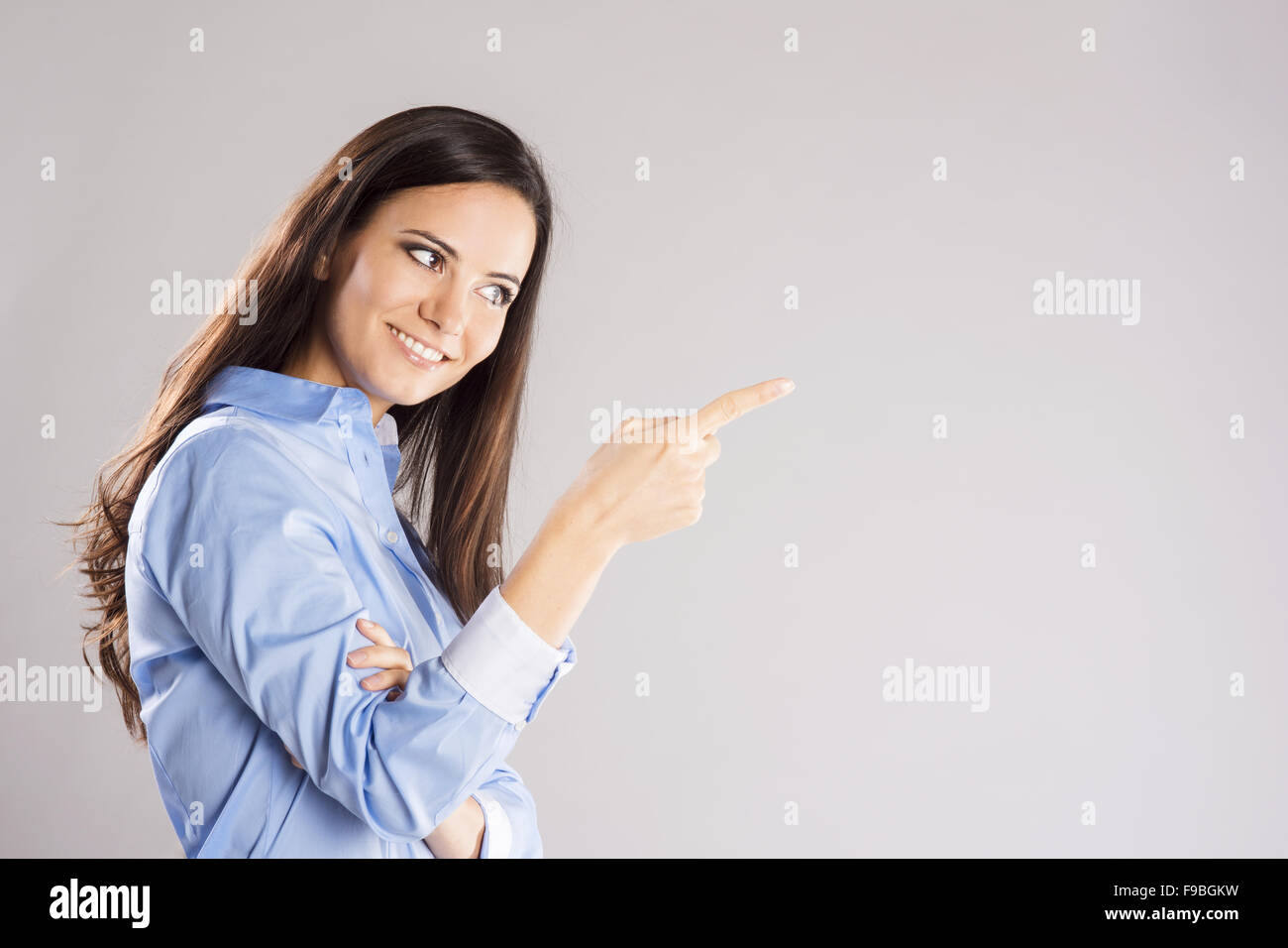 Beautiful young woman pointing to somewhere, isolated over a white ...