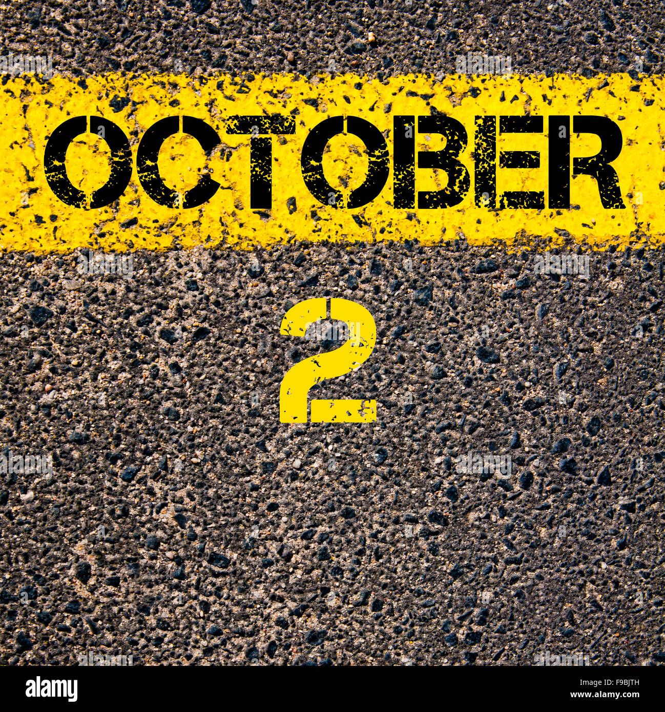 2 October calendar day written over road marking yellow paint line ...