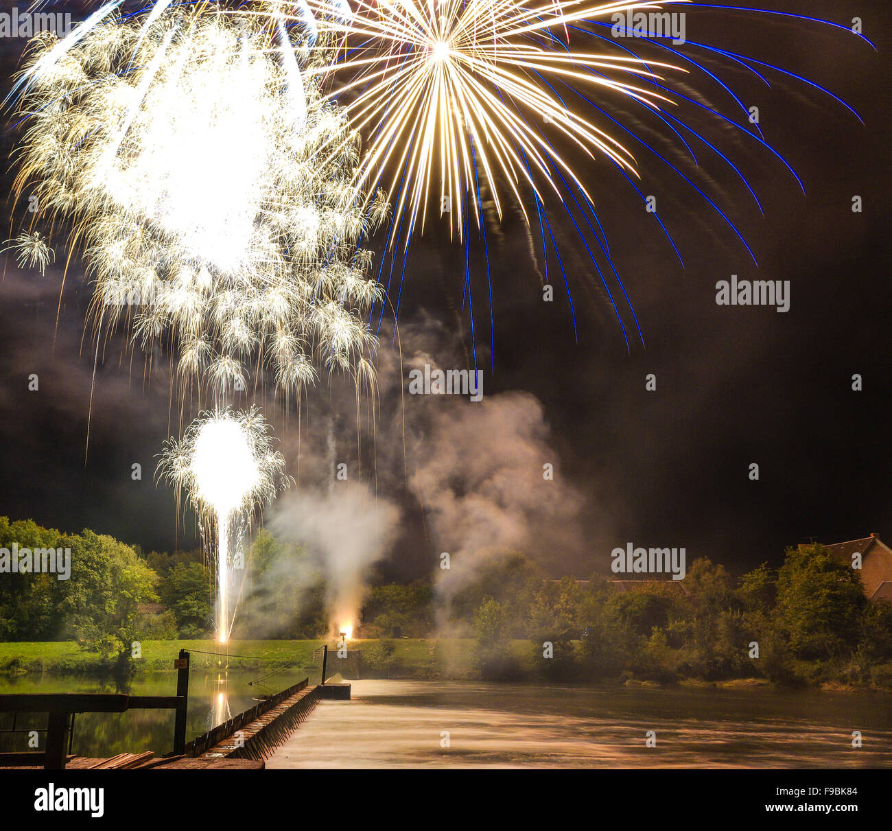 Fireworks bursting above a barrage on a French river with smoke trails ...