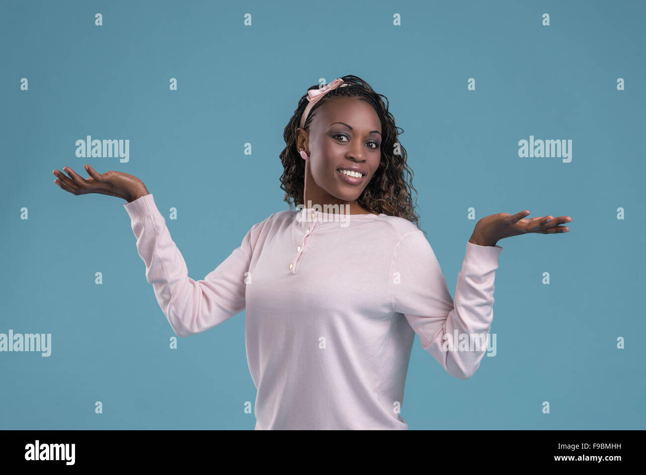 Beautiful African woman making a scale with her arms wide open on blue ...