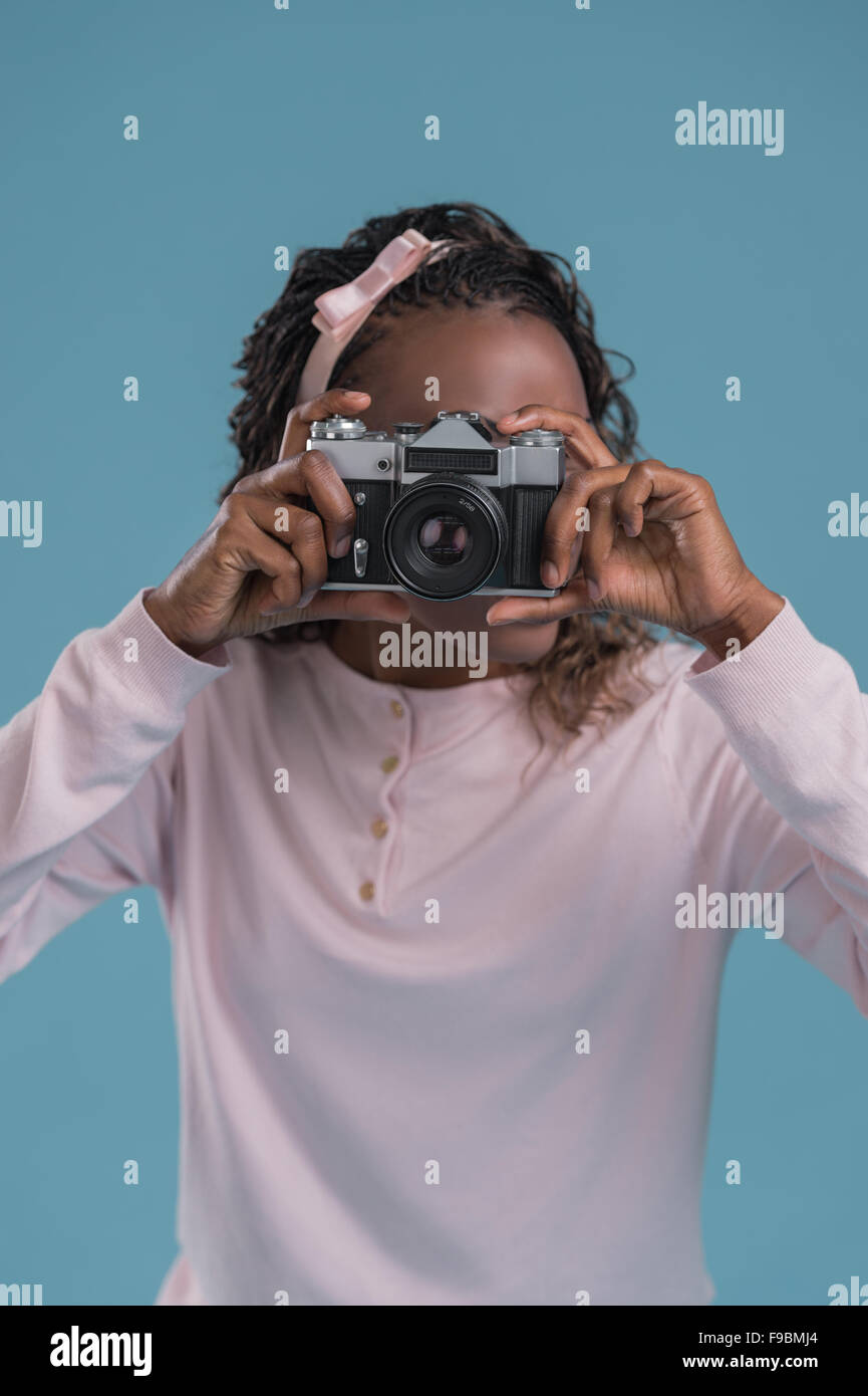 Beautiful young african woman using camera and photographing on blue ...