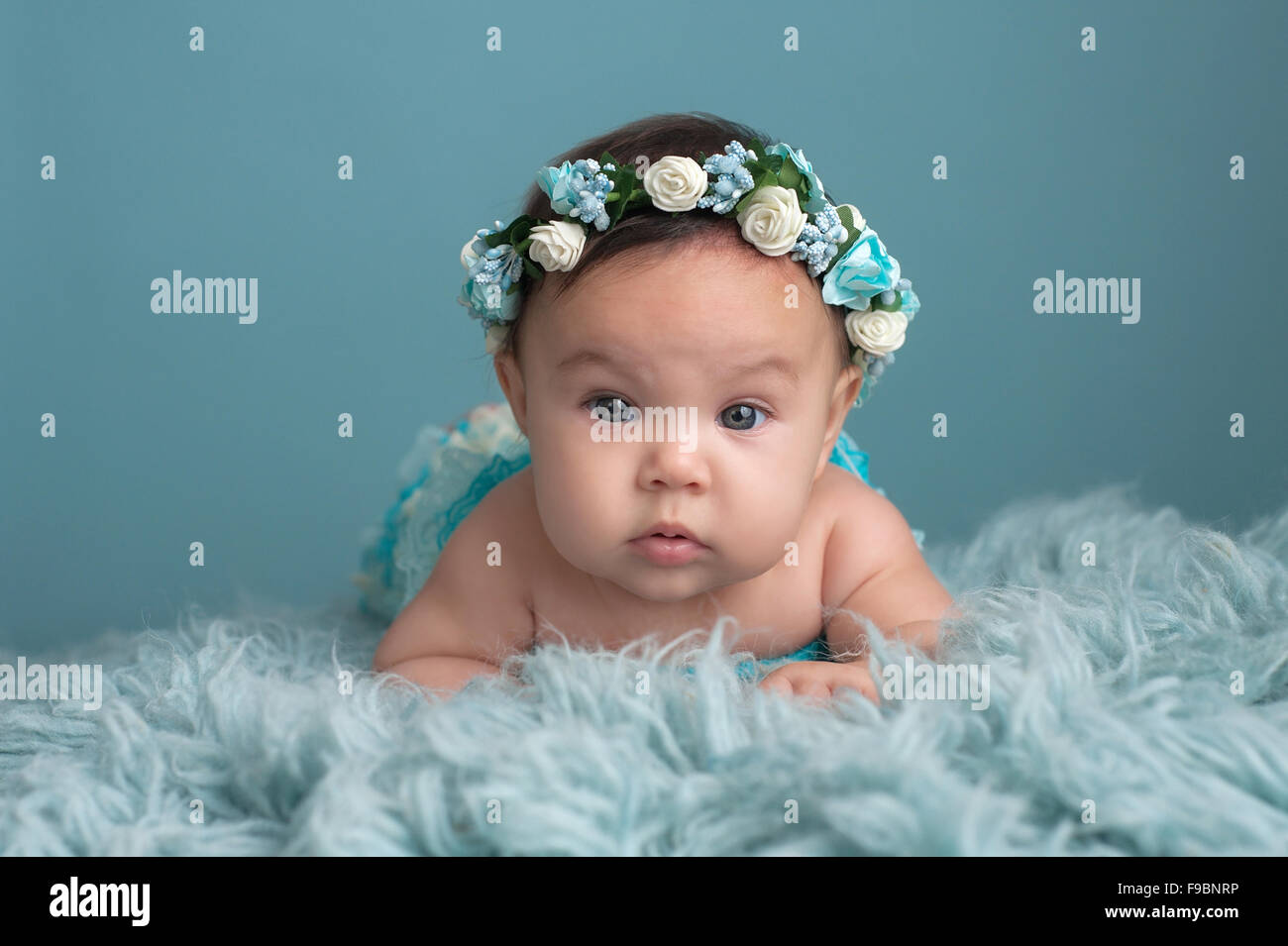 Studio portrait of a four month old baby girl propped up on her ...