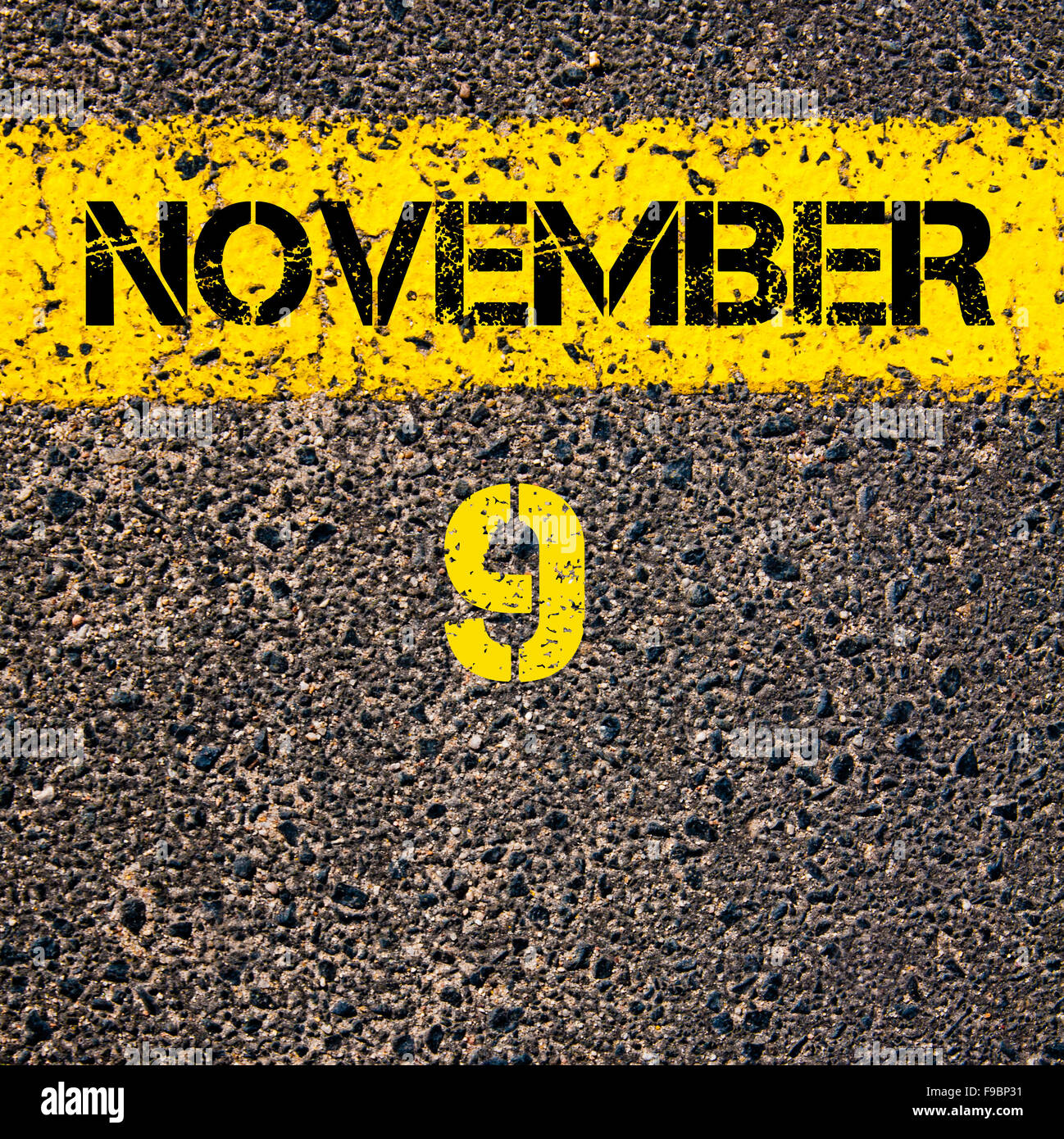 9 November calendar day written over road marking yellow paint line ...