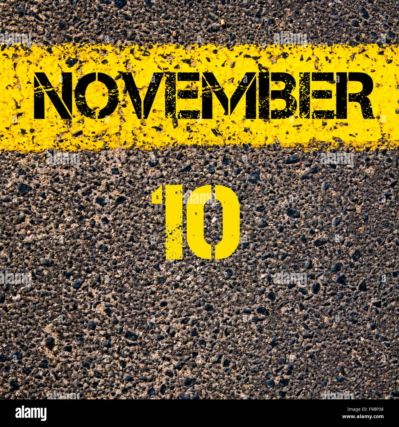 10 November calendar day written over road marking yellow paint line ...