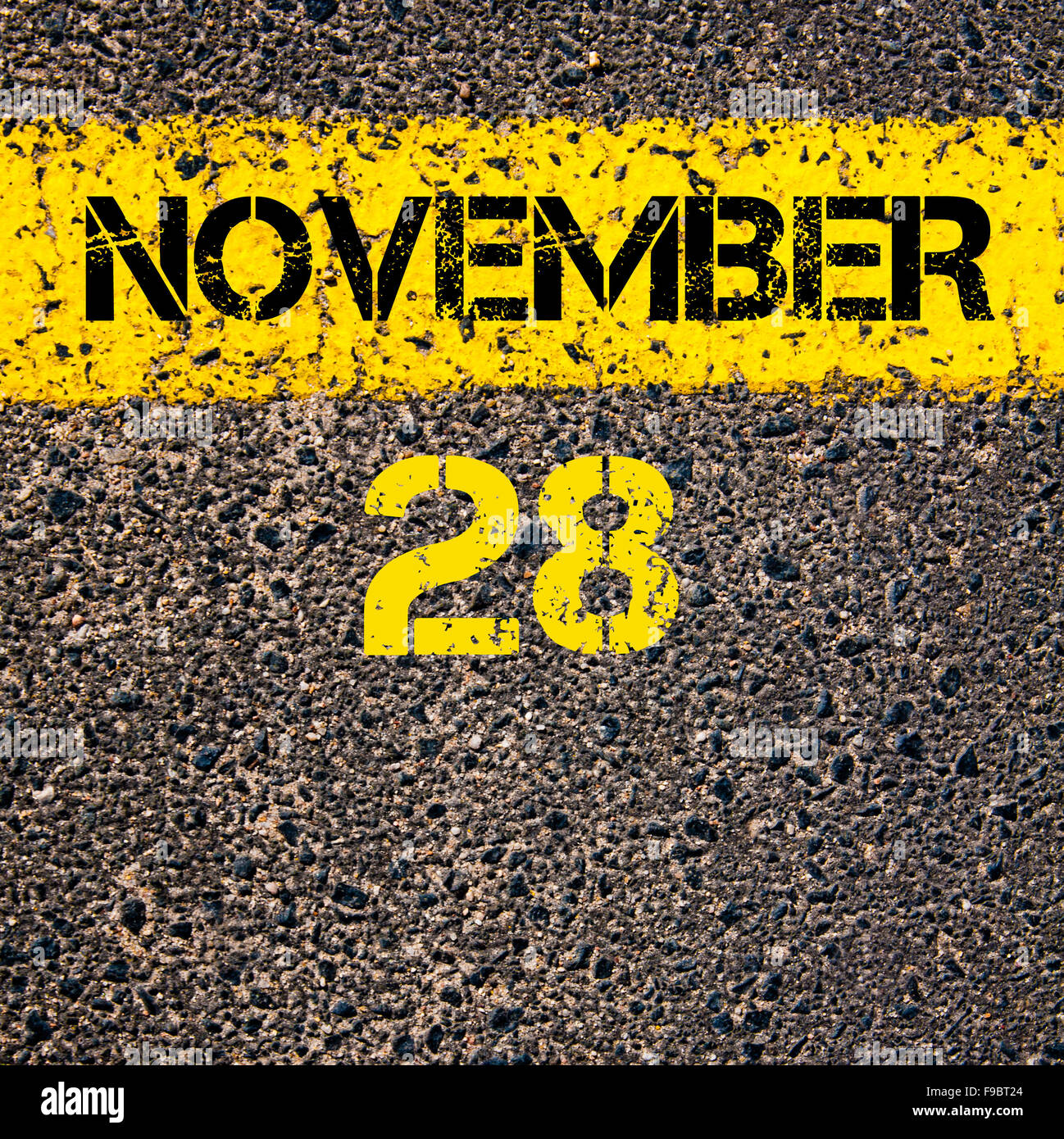 28 November calendar day written over road marking yellow paint line ...