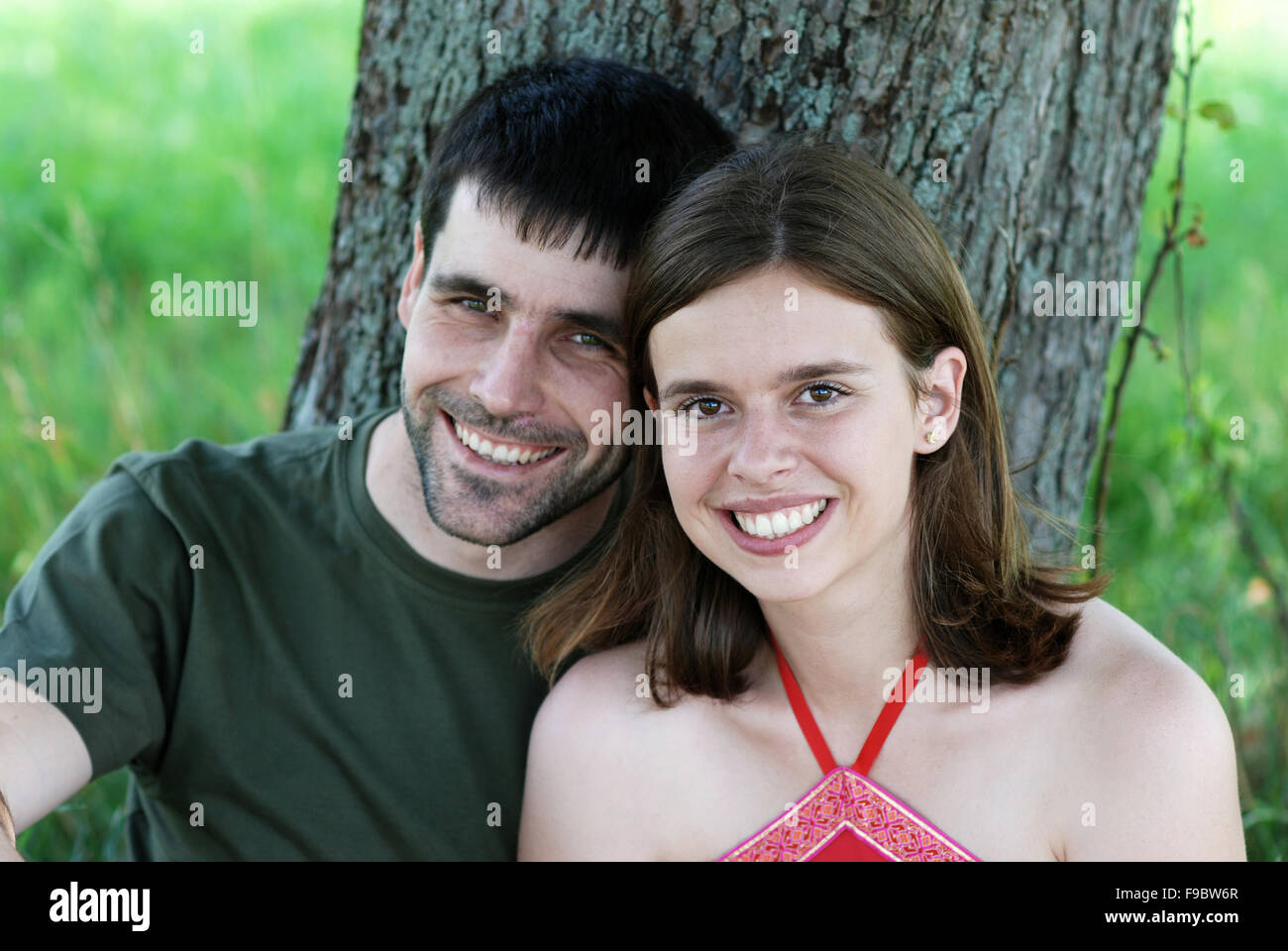 Couple is resting under tree Stock Photo - Alamy
