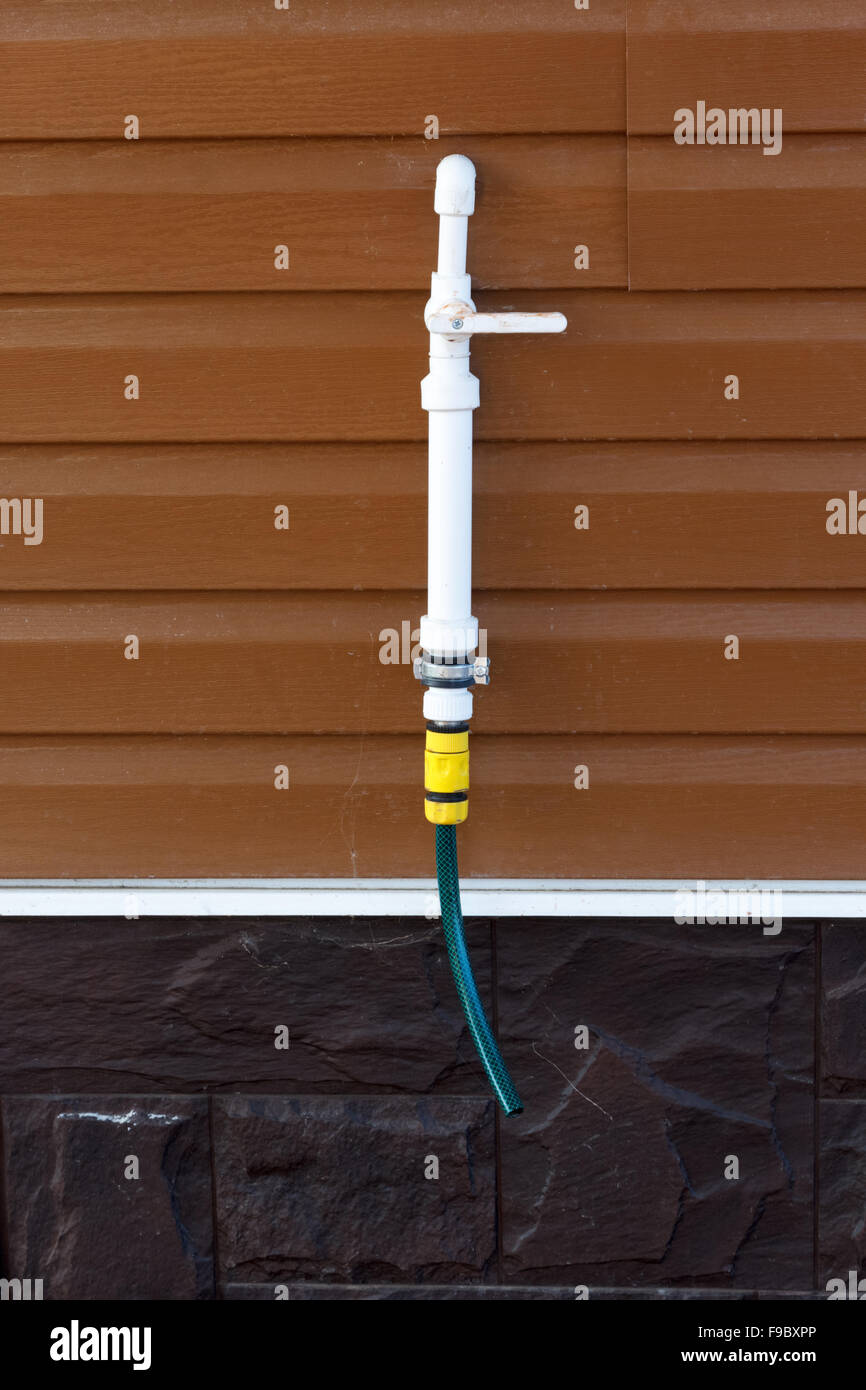 Polypropylene pipe with a tap on a siding wall Stock Photo - Alamy