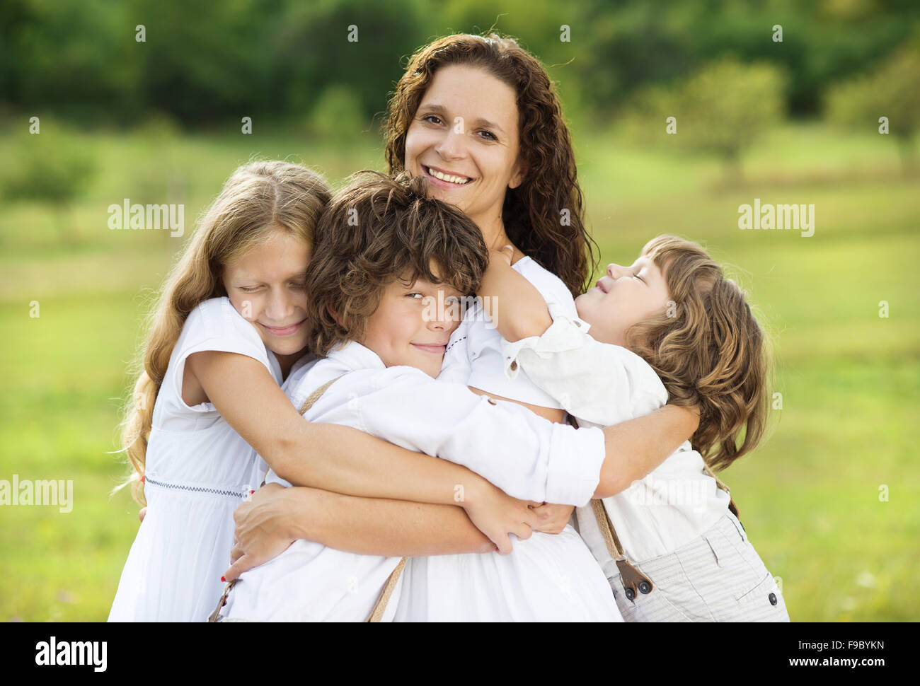 Children giving hugs to their mum on the meadow Stock Photo - Alamy