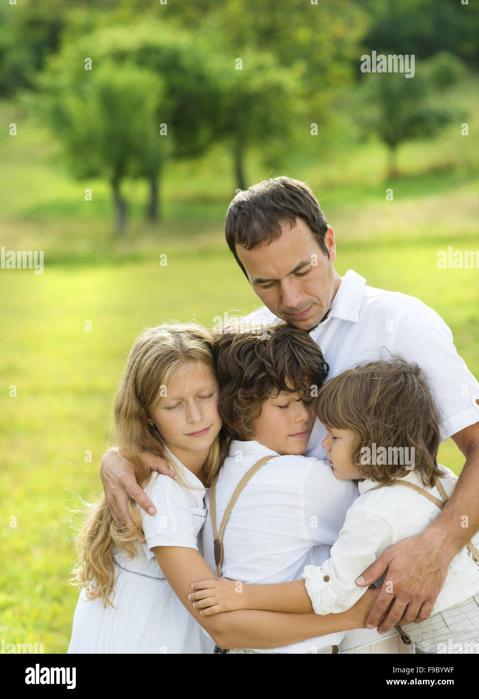 Children giving hugs to their dad on the meadow Stock Photo - Alamy