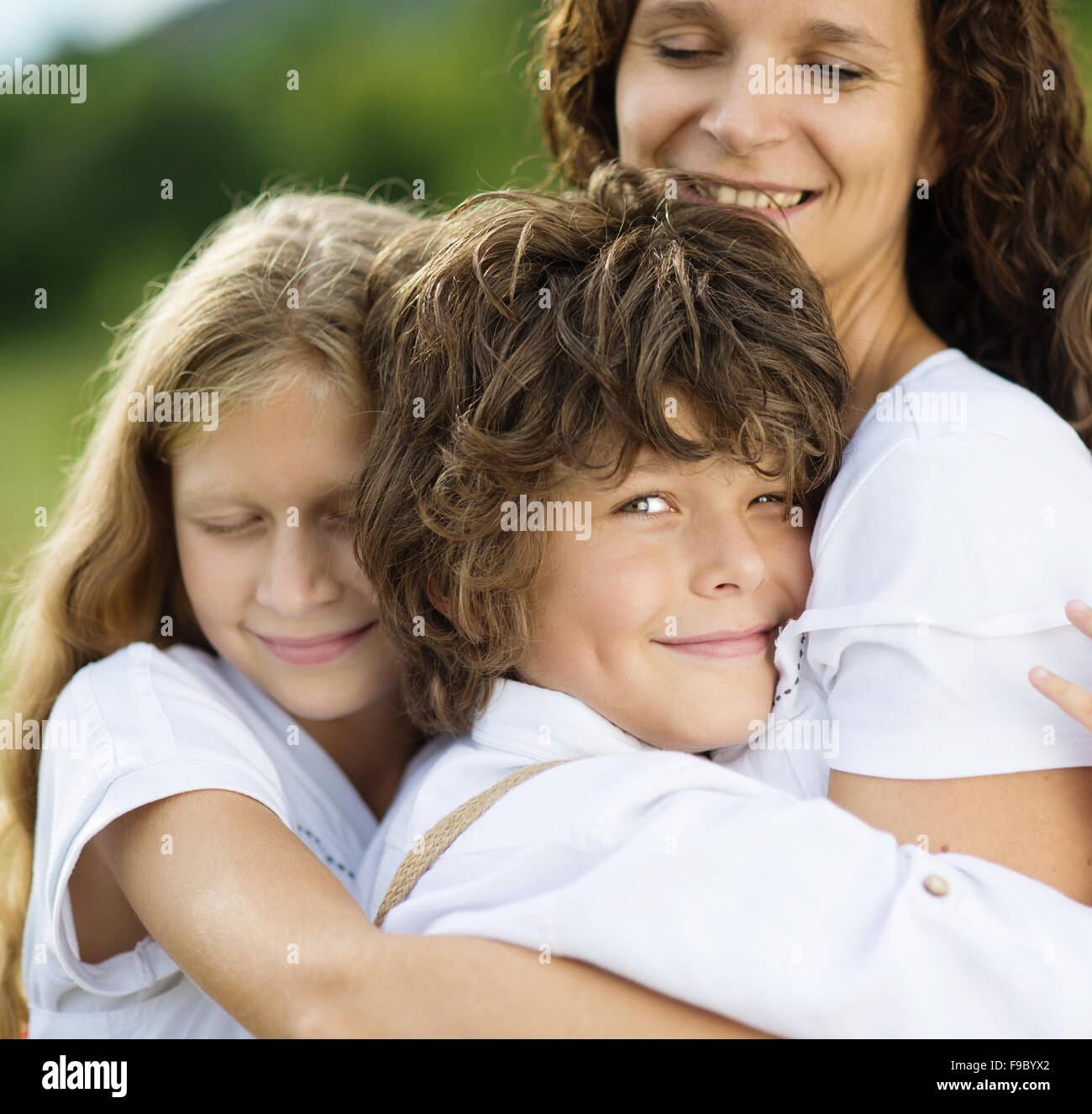 Children giving hugs to their mum on the meadow Stock Photo - Alamy