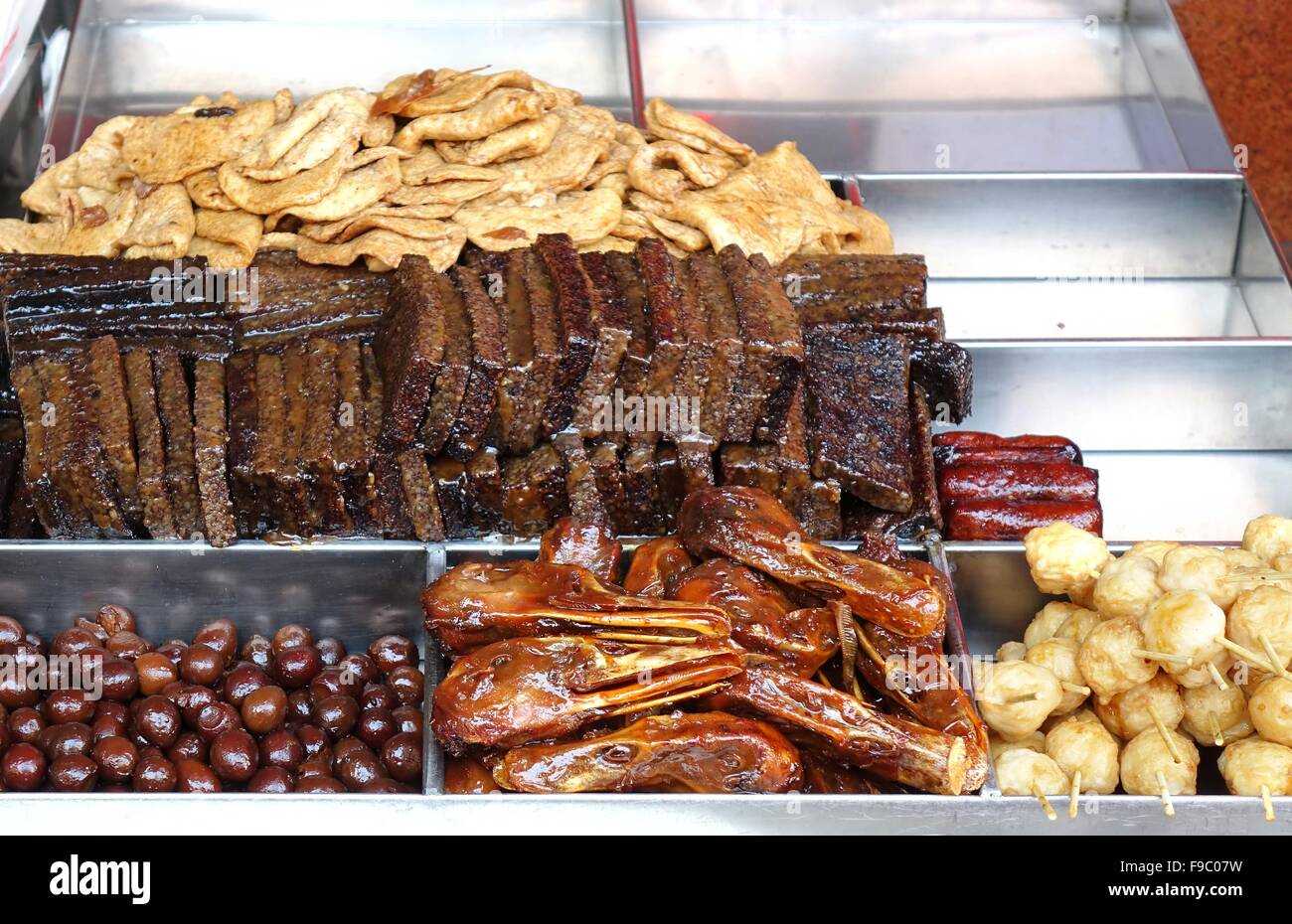 A market stall sells traditional foods such as duck heads, rice and ...