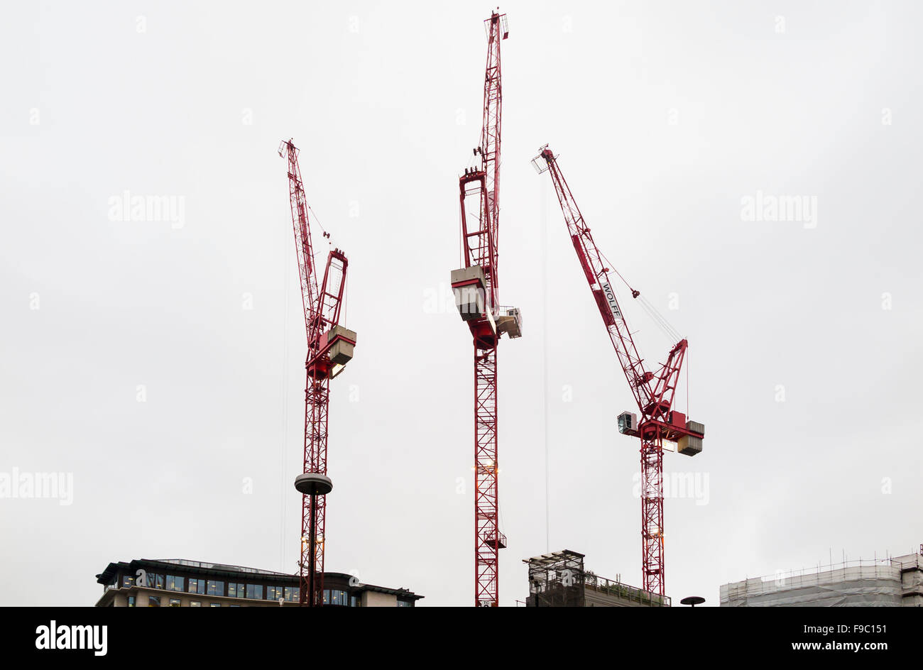 Three red tower cranes against a white sky in the evening at the Arthur ...