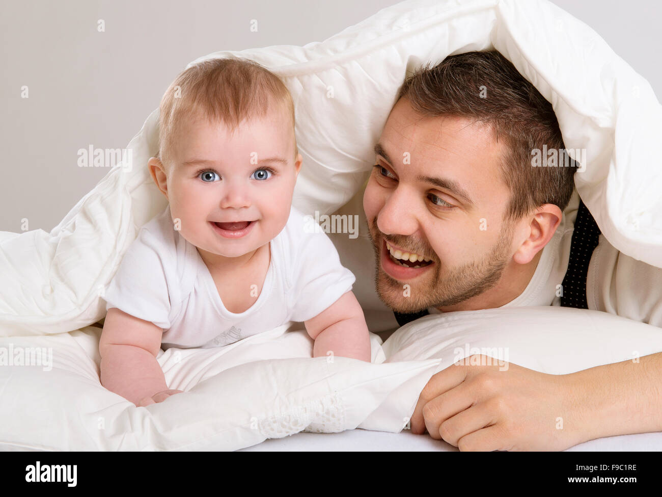 Young father is playing with baby in bed Stock Photo - Alamy