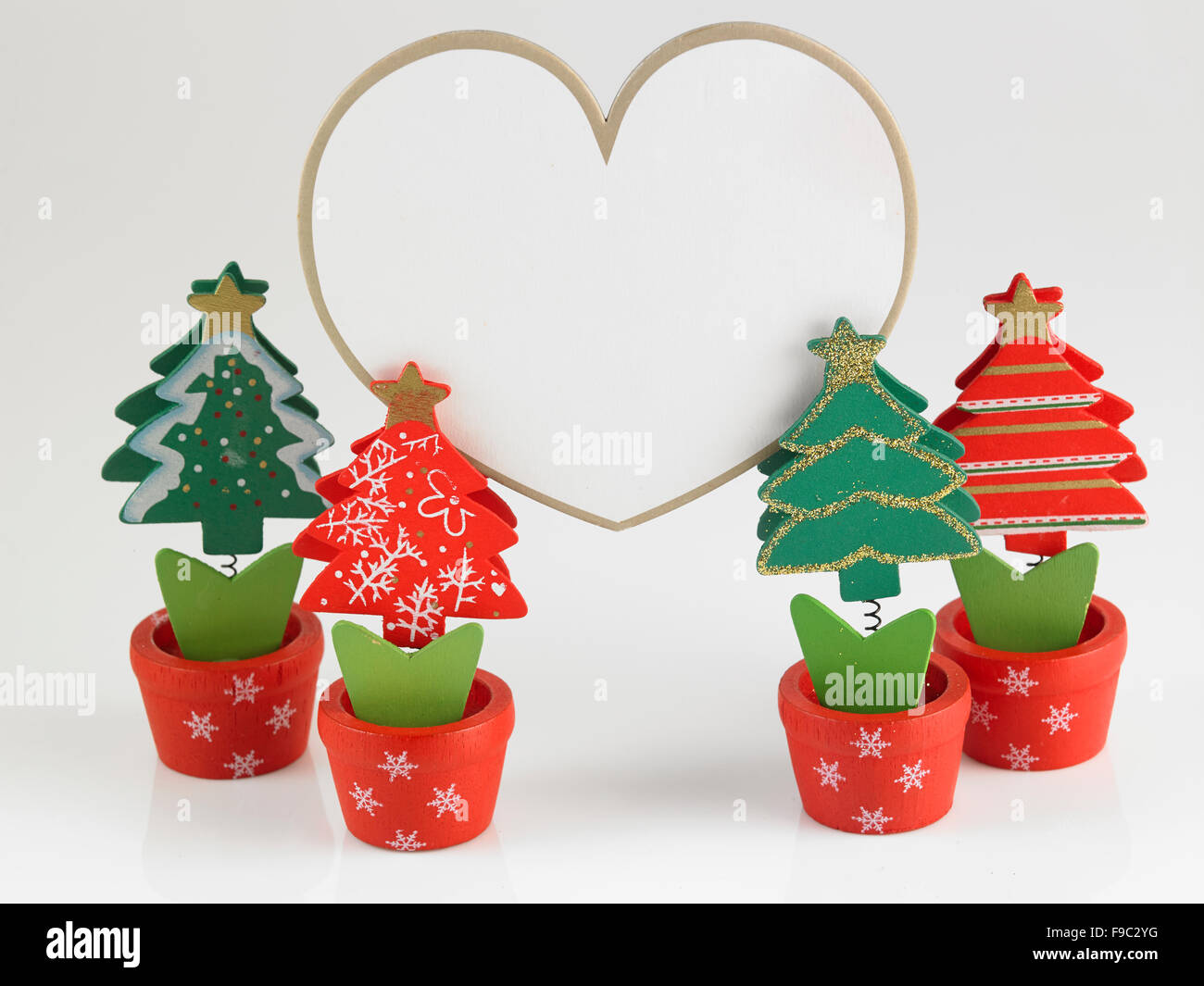 hand made christmas trees holding a blank heart shape cardboard Stock ...